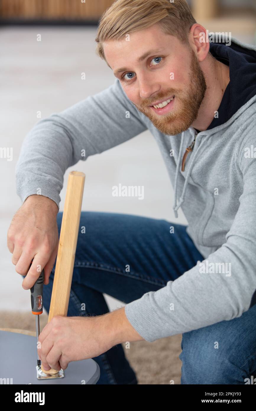 handsome young working man repairing wooden stool using screwdriver ...