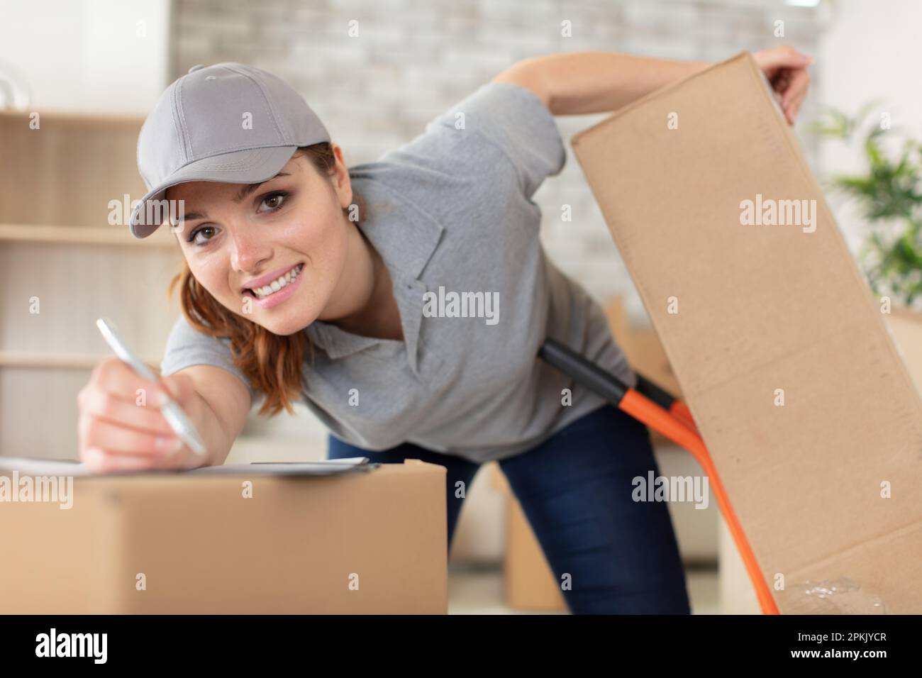 delivery woman writing on clipboard while balancing packages Stock ...