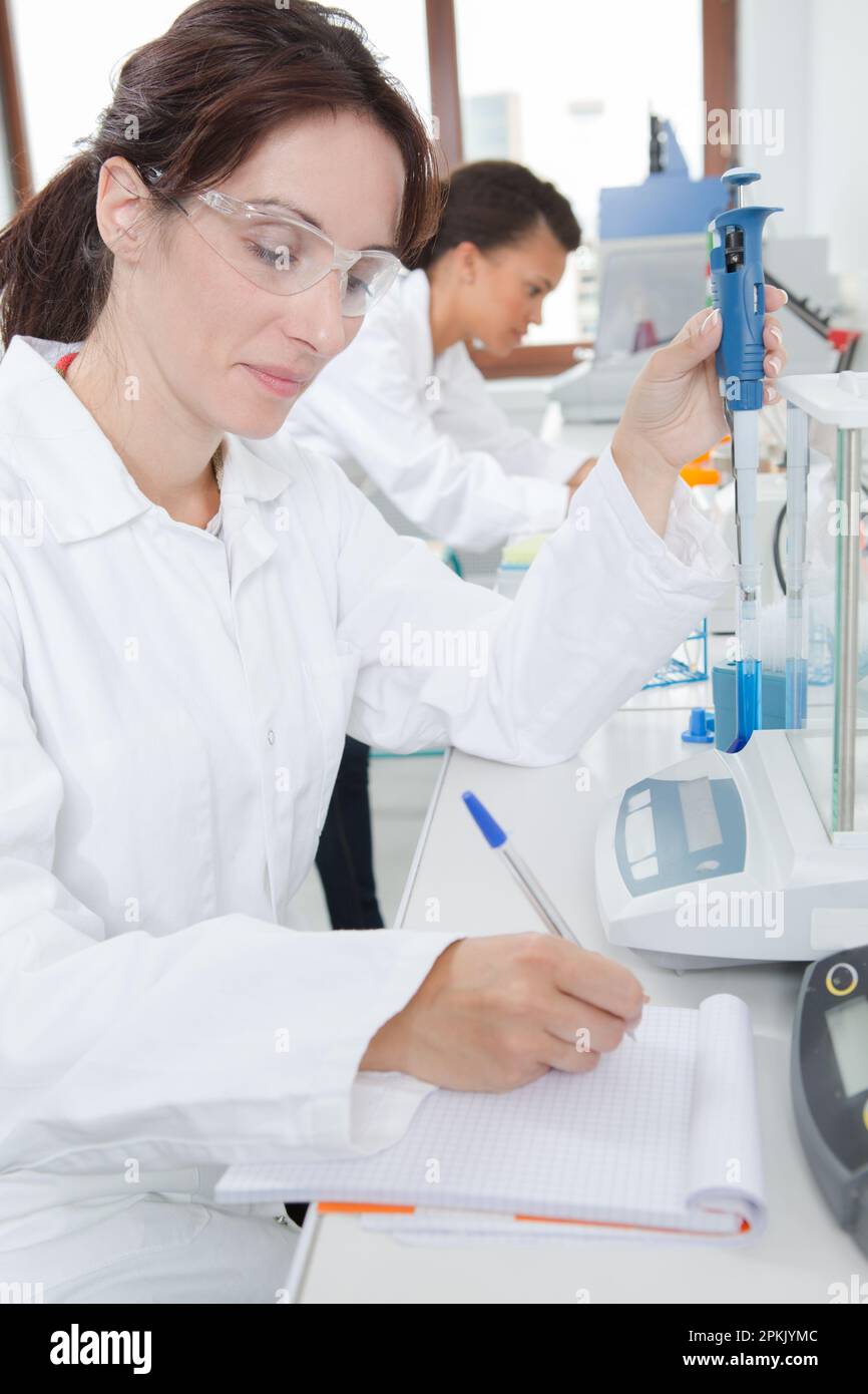 female scientist making notes as she conducts experiment Stock Photo ...