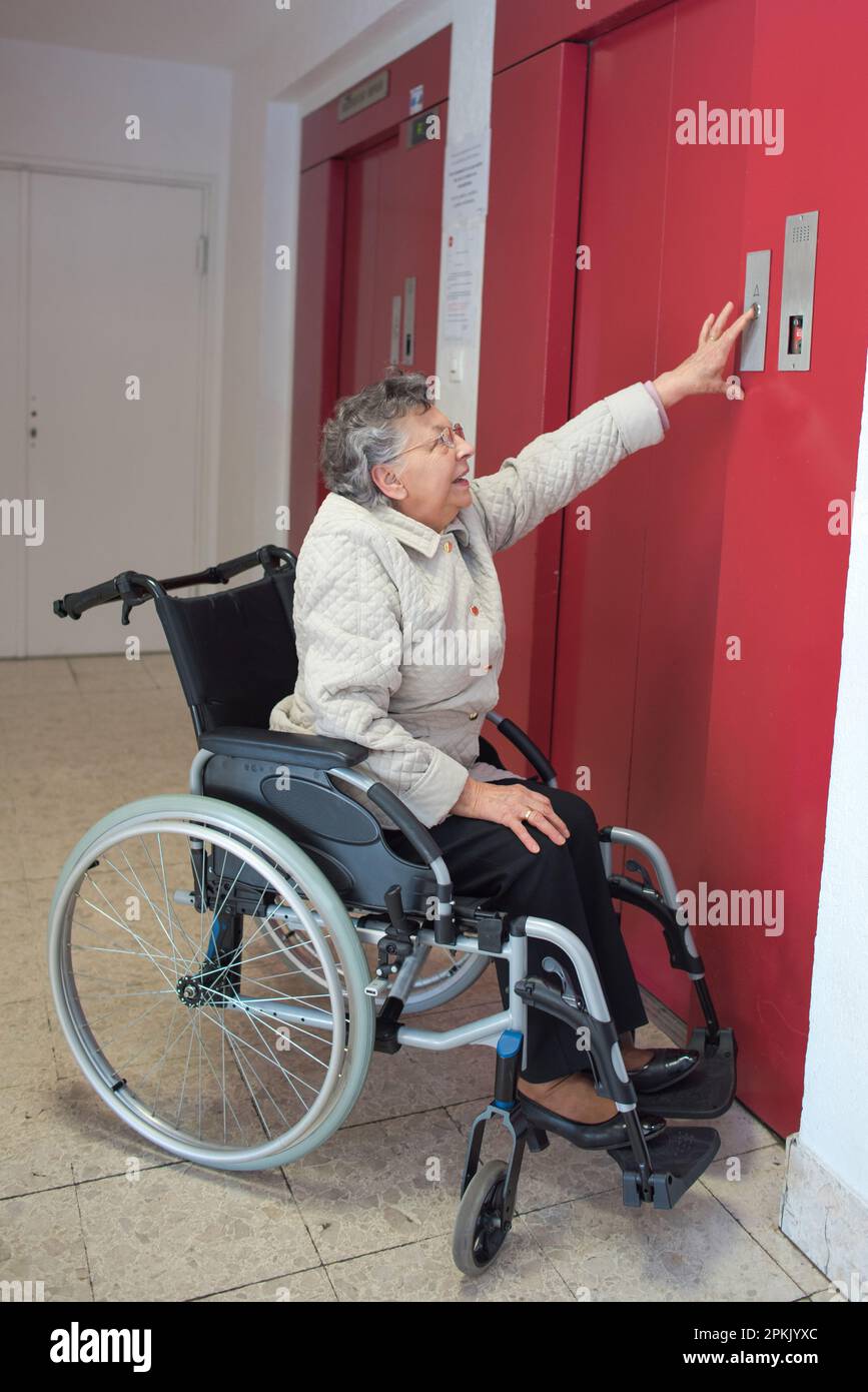 elderly woman in wheelchair alone getting into the elevator Stock Photo ...