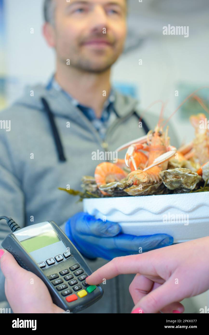 Customer entering code in card machine paying for seafood platter Stock ...
