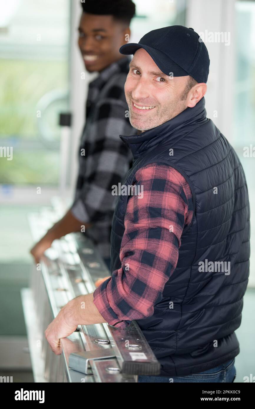 two builder carrying ladder together Stock Photo - Alamy