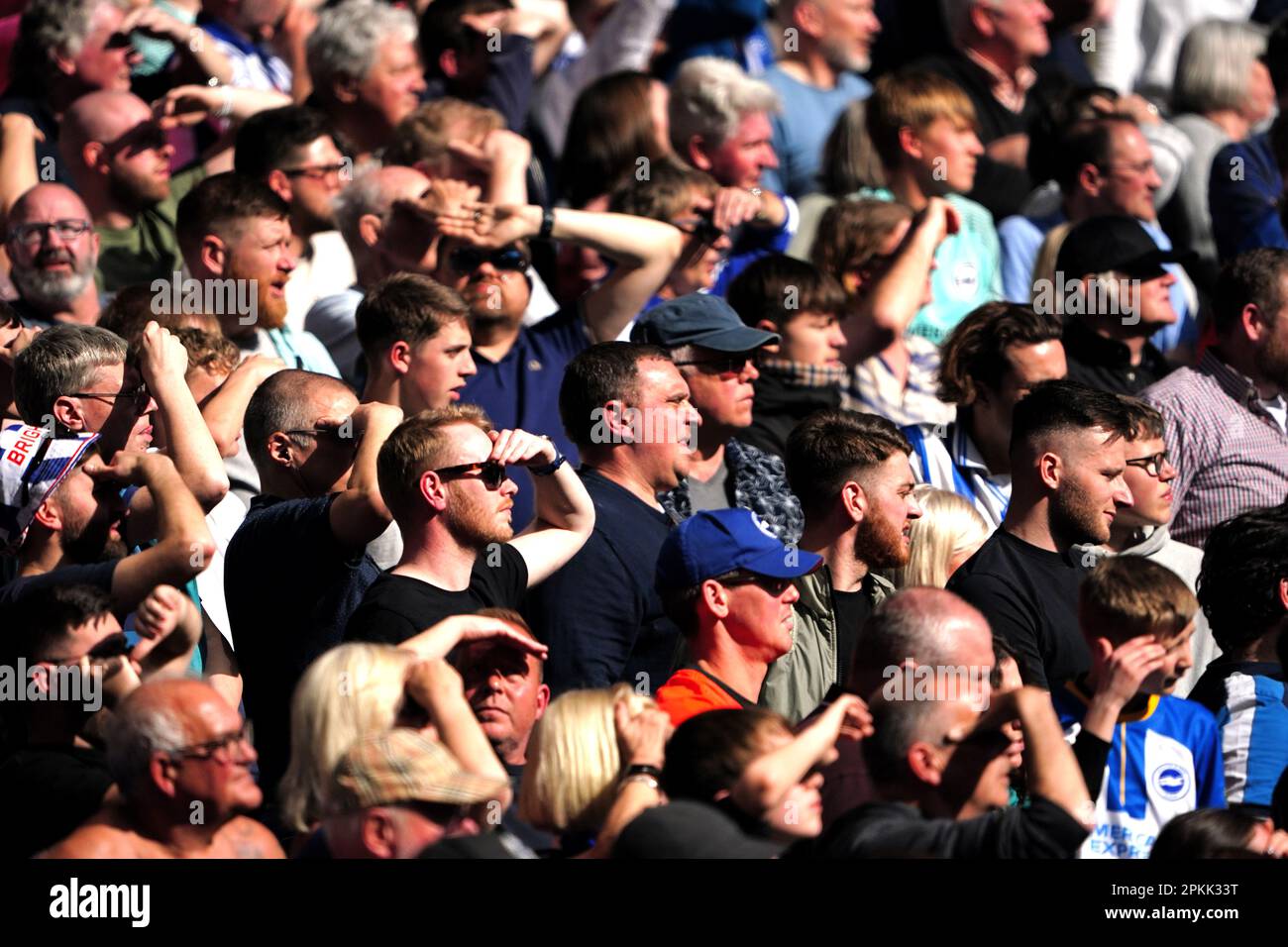 Fans shield their eyes from the sun during the Premier League match at ...