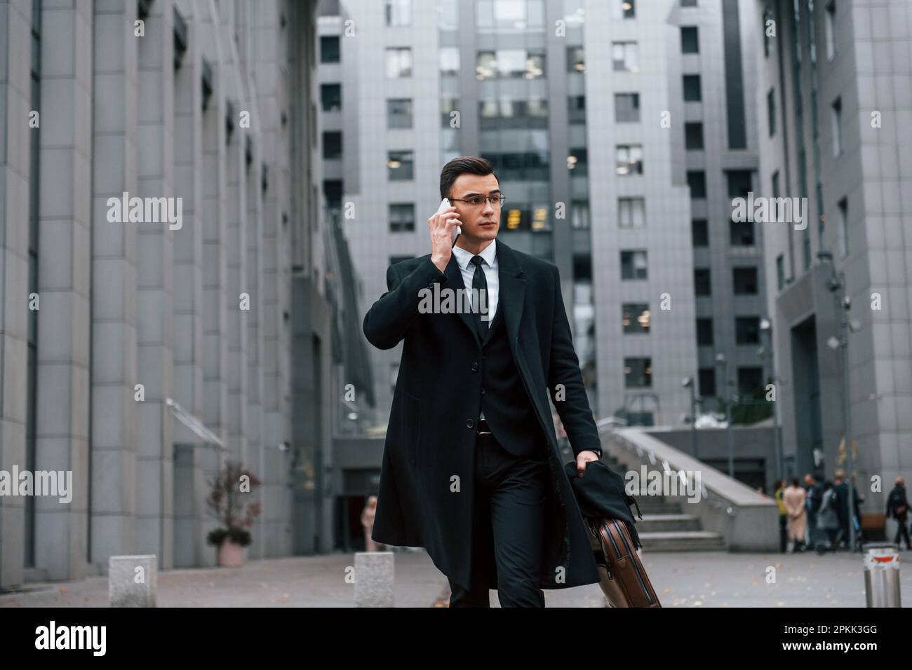 In formal clothes. Businessman in black suit and tie is outdoors in the ...