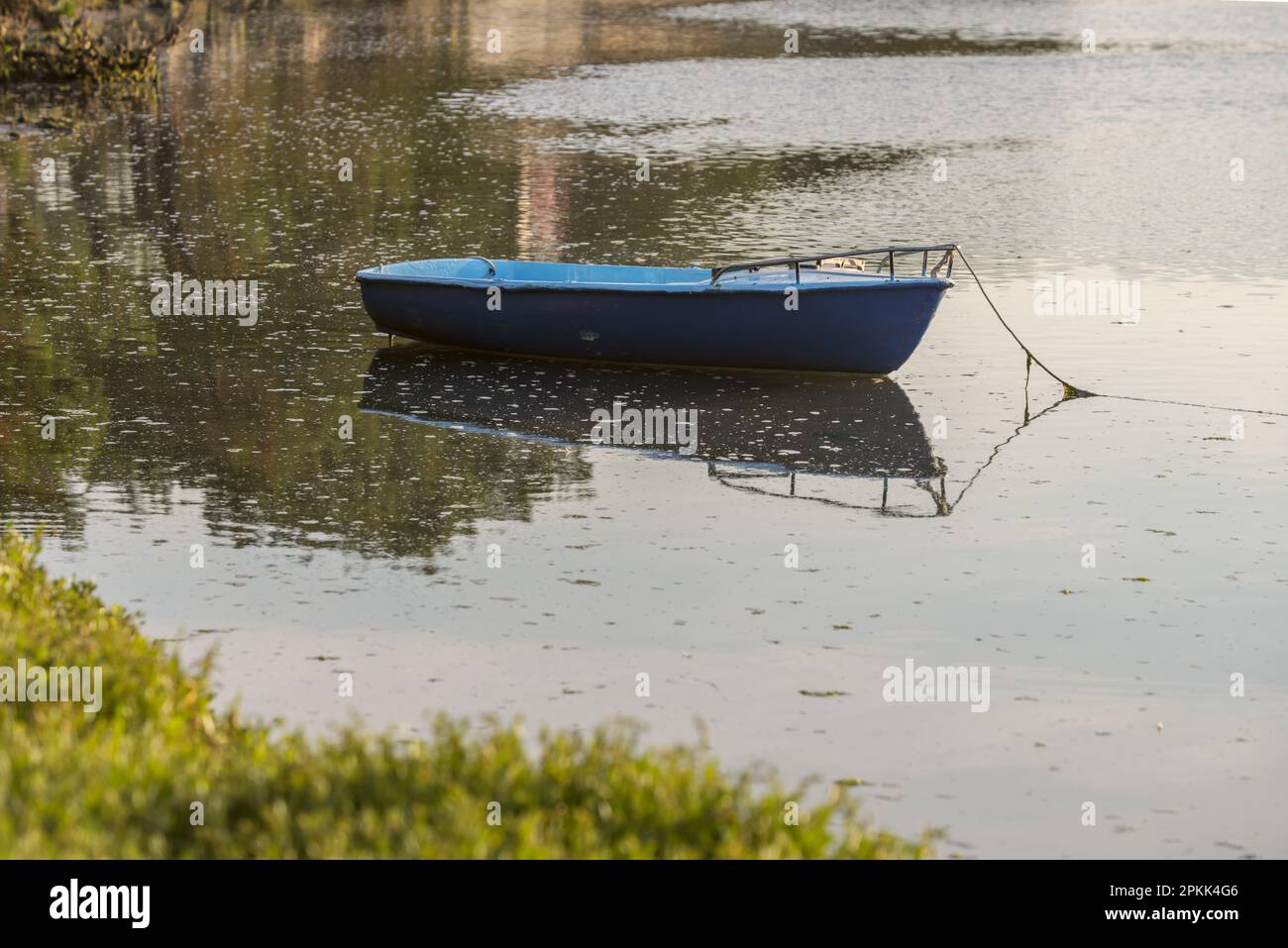 A small blue raft tied with a rope on the water surface of a lagoon ...