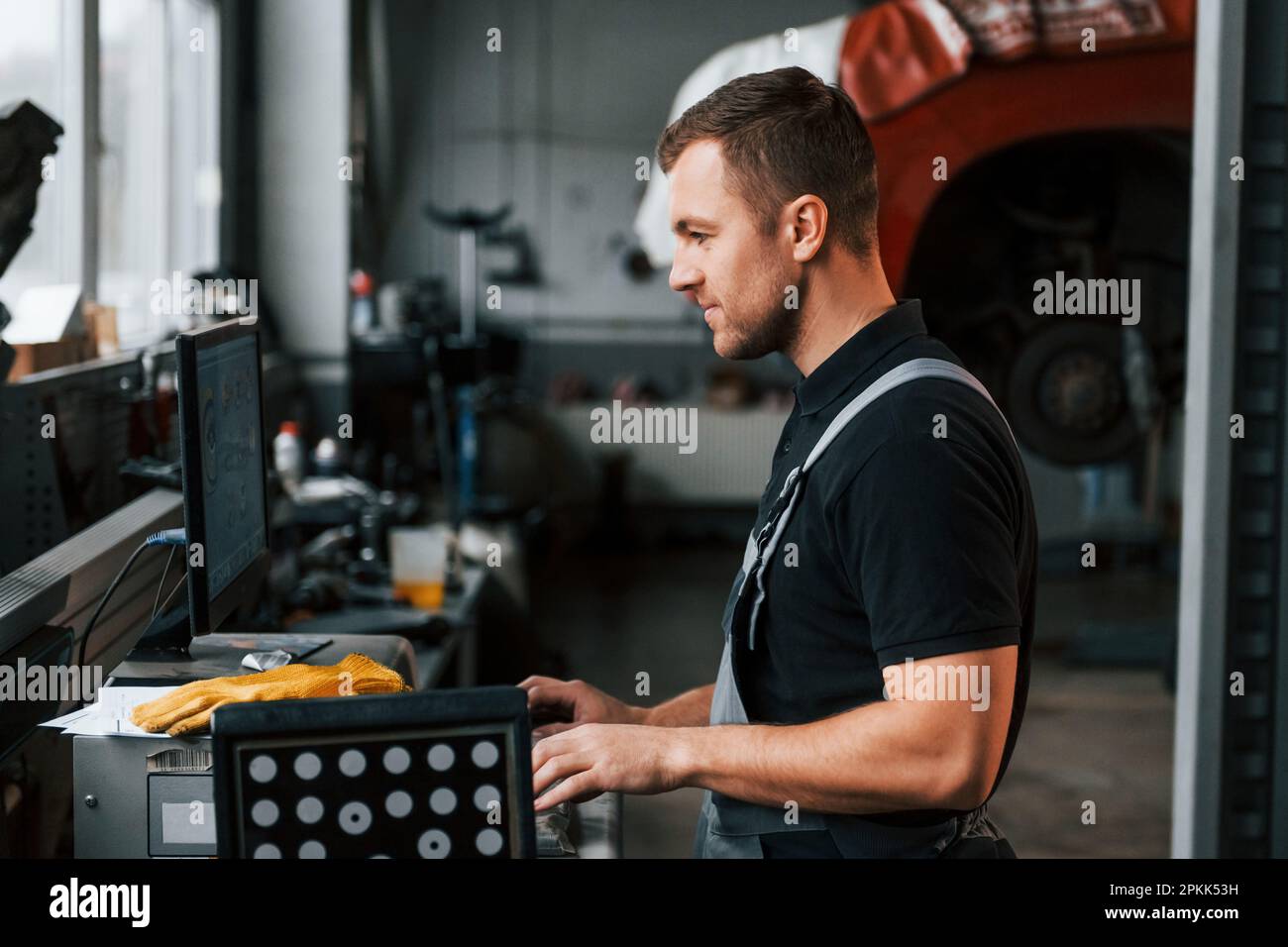 Work in progress. Man in uniform is in the auto service Stock Photo - Alamy