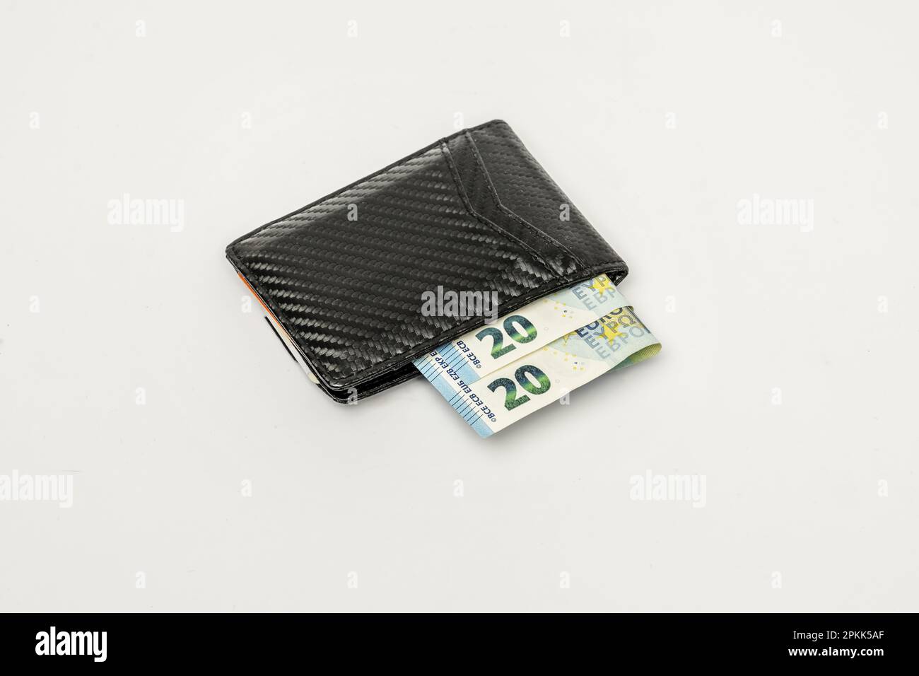A black carbon fiber braided wallet filled with euro banknotes on a ...