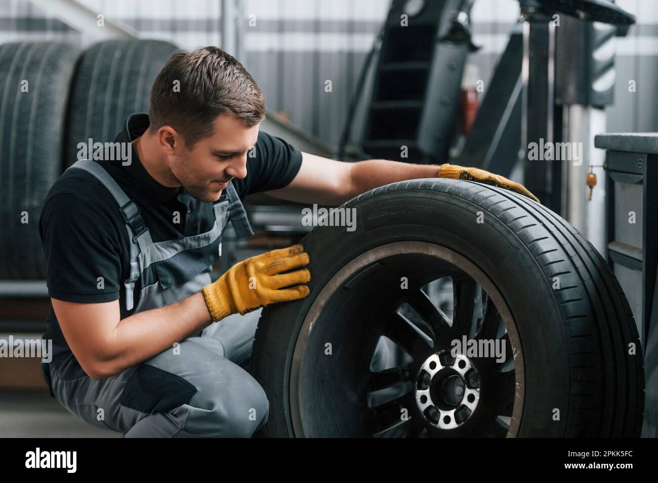 Replacement of the old tire. Man in uniform is working in the auto ...