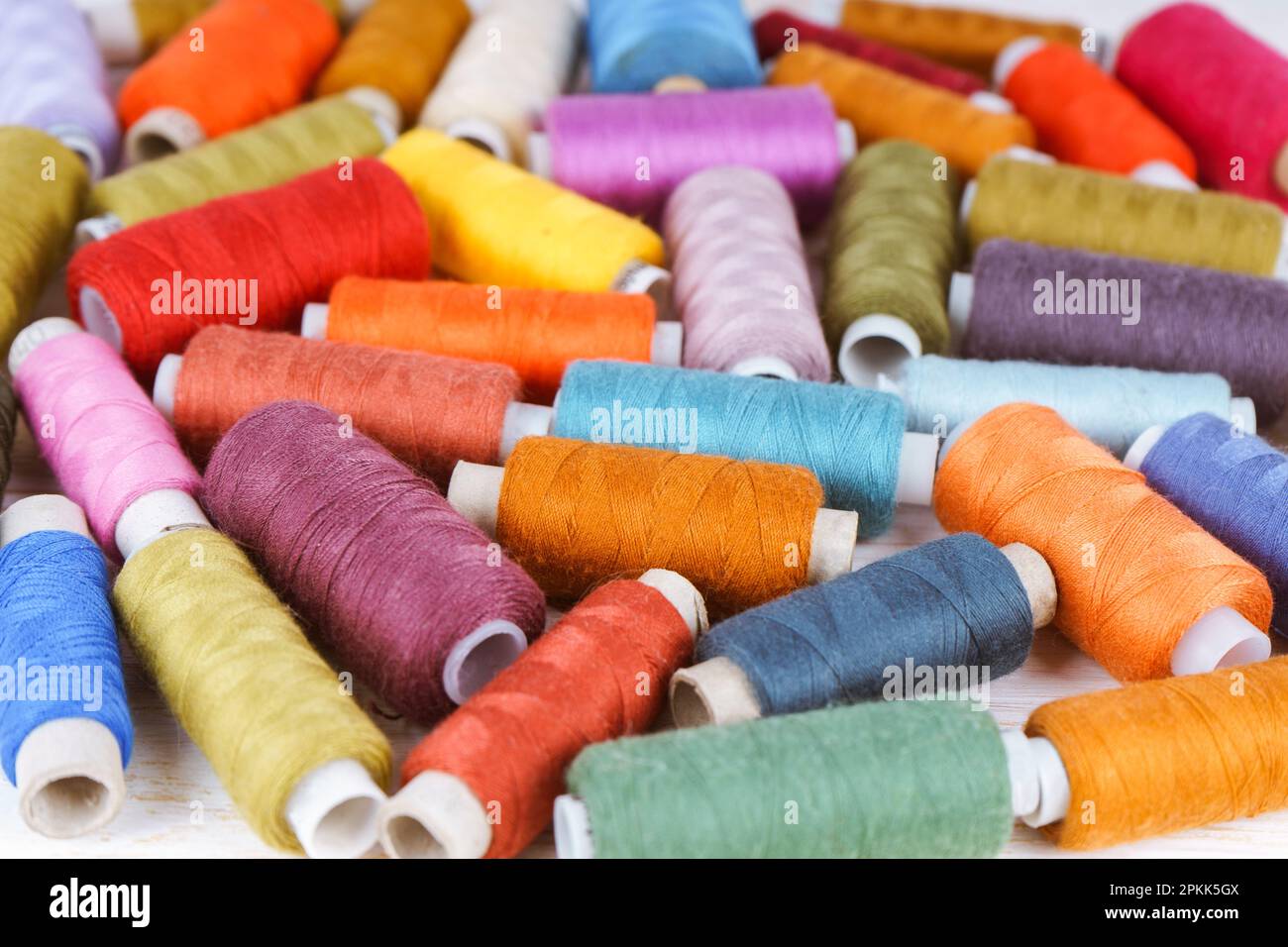 Scattering of various colors sewing threads on white wooden background ...