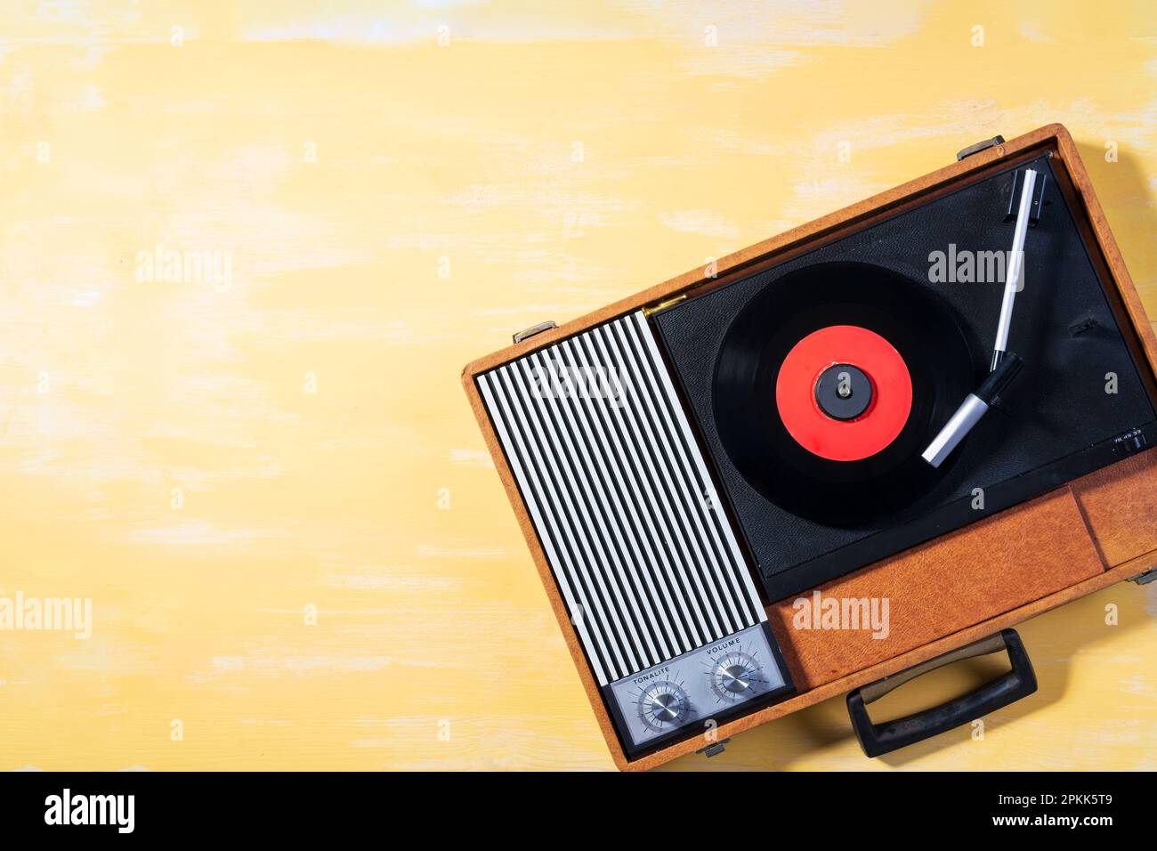 Old gramophone with a vinyl record on yellow wooden table, top view ...