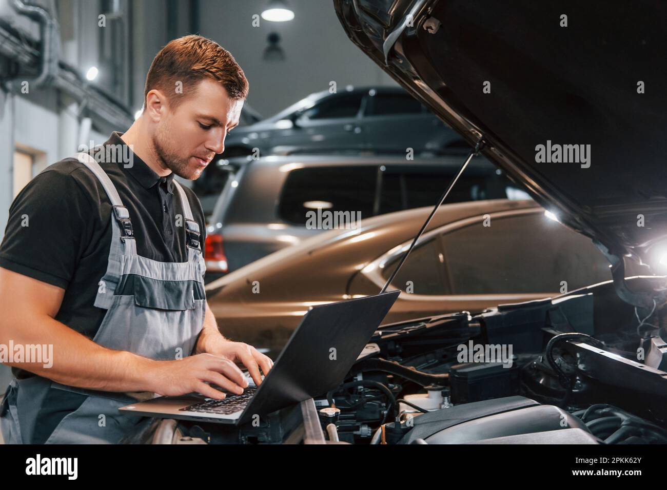 Side view. Man in uniform is working in the auto service Stock Photo ...