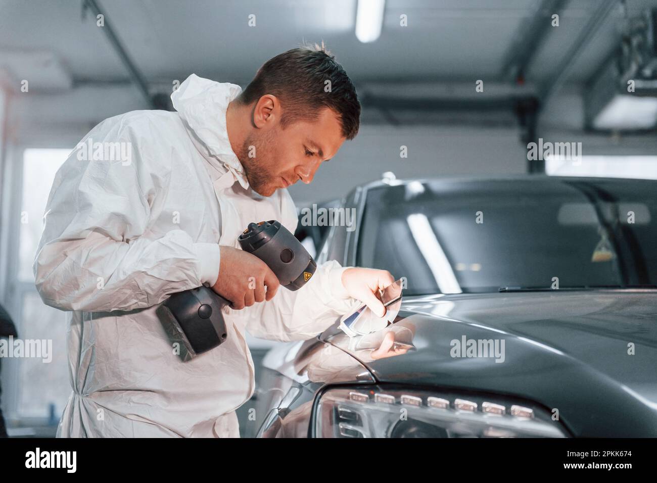 Using special equipment. Man in uniform is working in the auto service ...