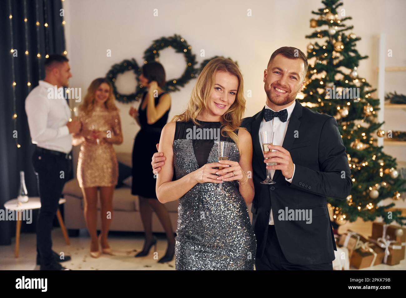 Beautiful couple. Group of people have a new year party indoors ...
