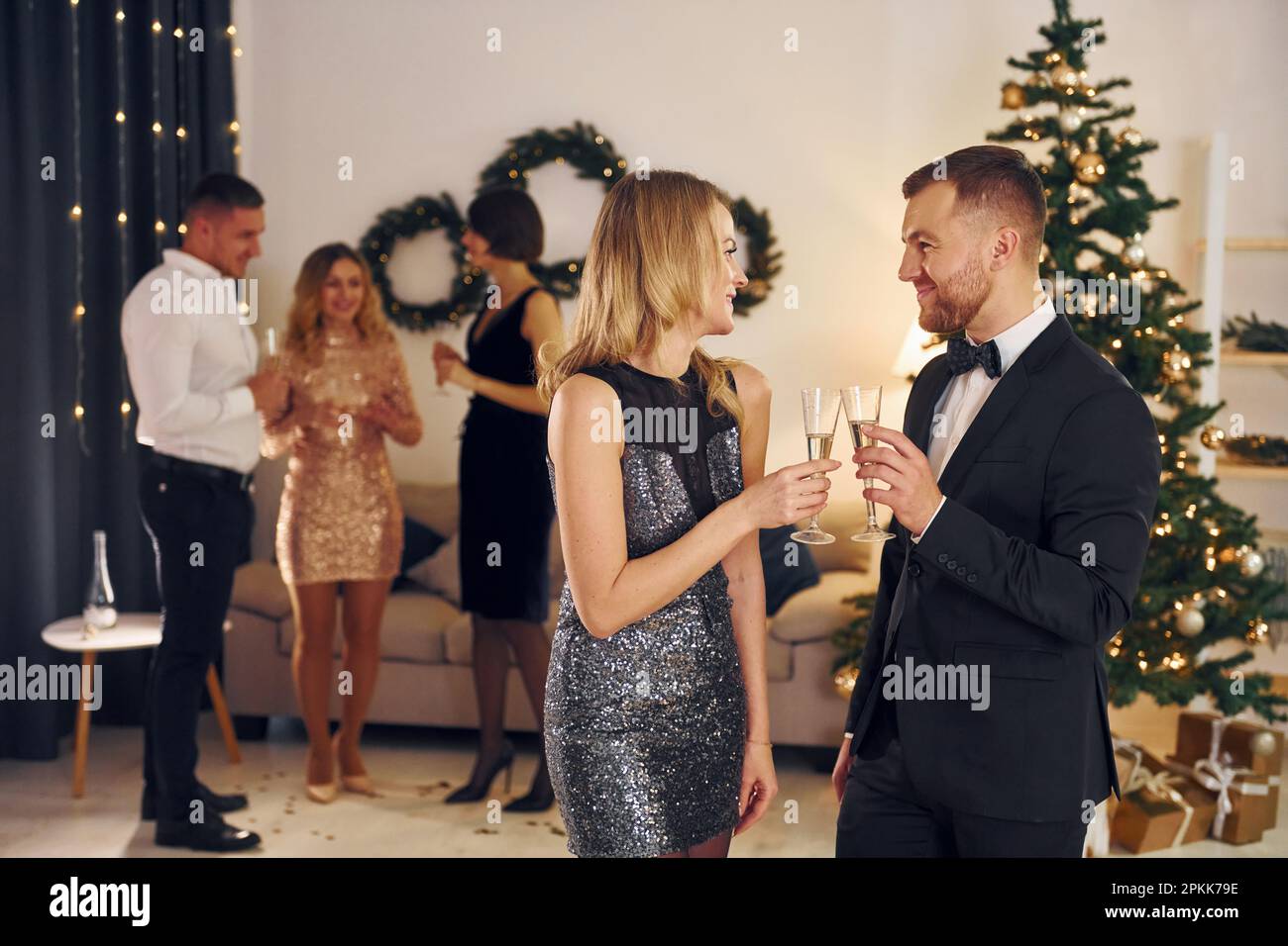 Beautiful couple. Group of people have a new year party indoors ...