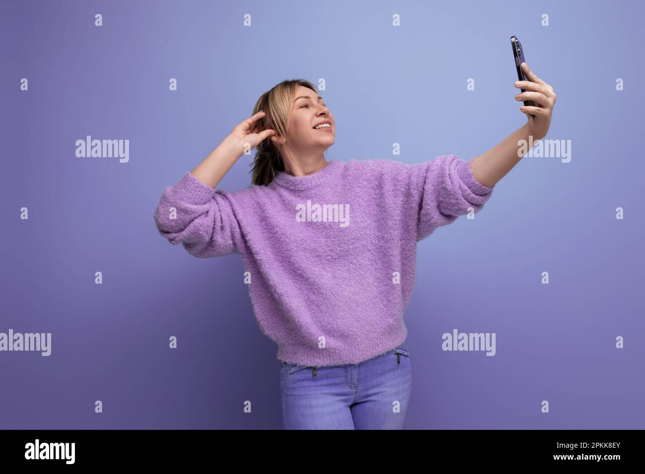 charming blond young millennial woman in a casual look takes a selfie ...