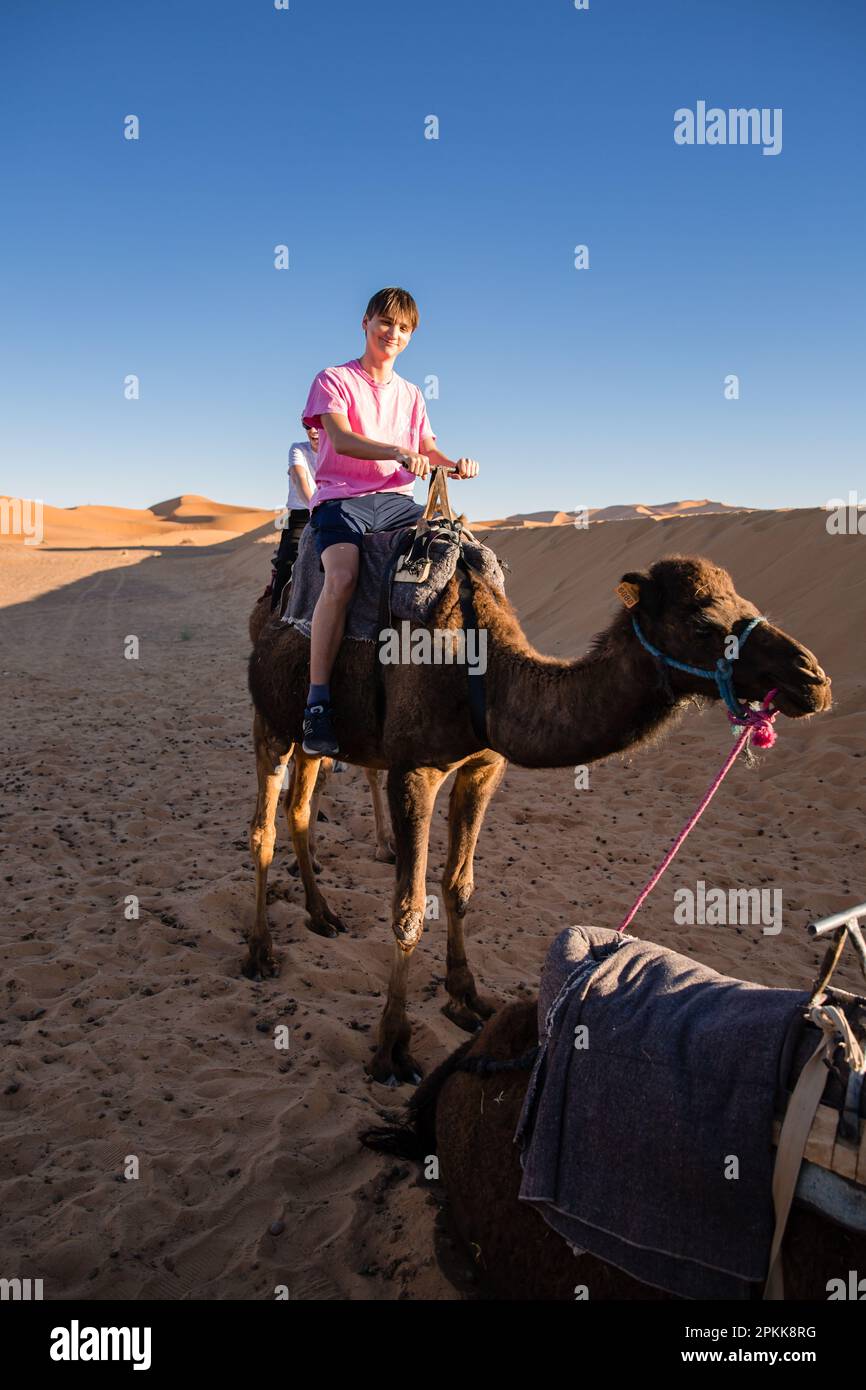 An American teenaged boy rides a camel in the Sahara Desert Stock Photo ...