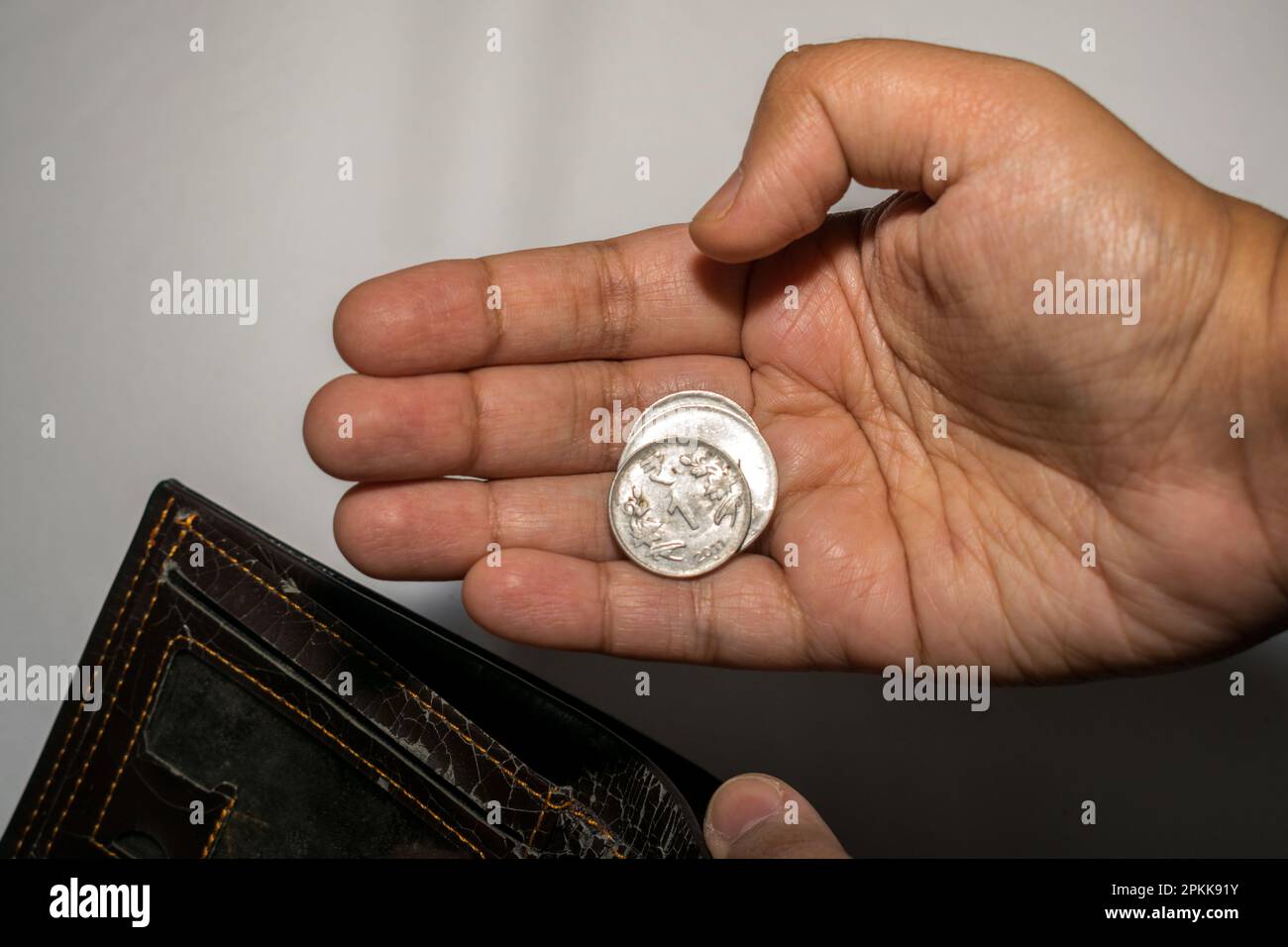 A businesswoman, holding a few Indian rupee coins, unemployed and ...