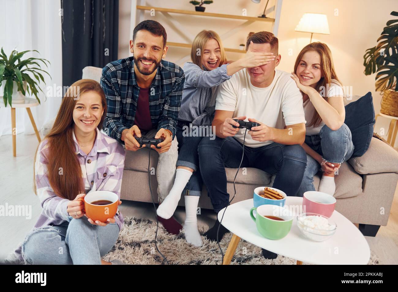 Using joysticks to play video game. Group of friends have party indoors ...