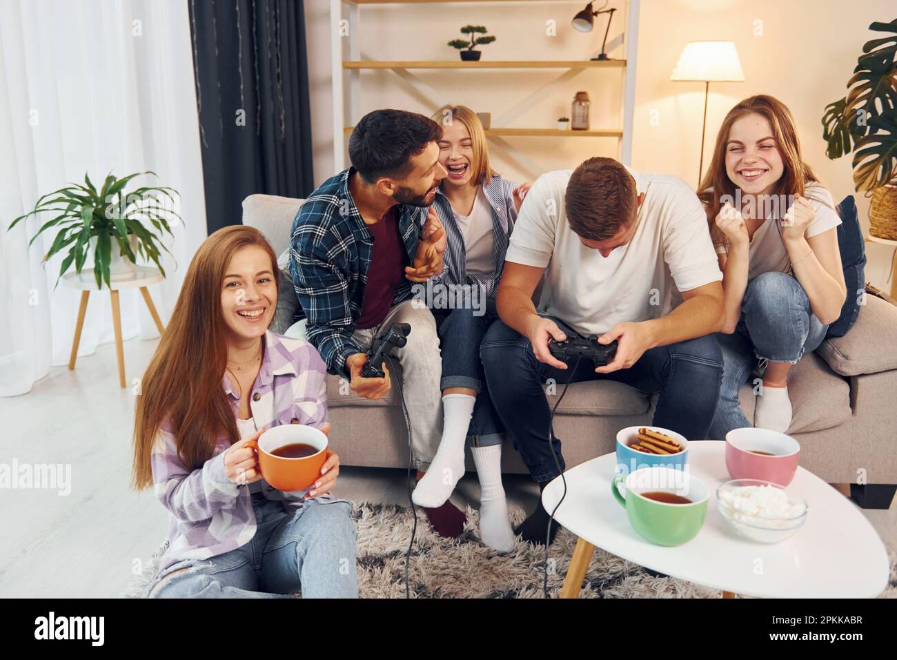Using joysticks to play video game. Group of friends have party indoors ...