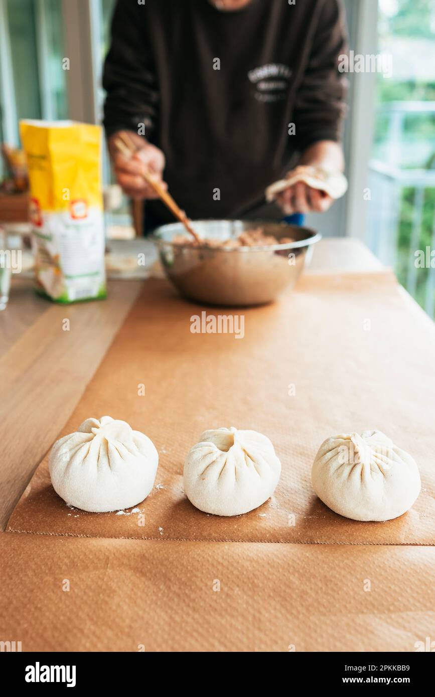 A woman makes bao in the kitchen. Bao, also known as baozi. It's a ...