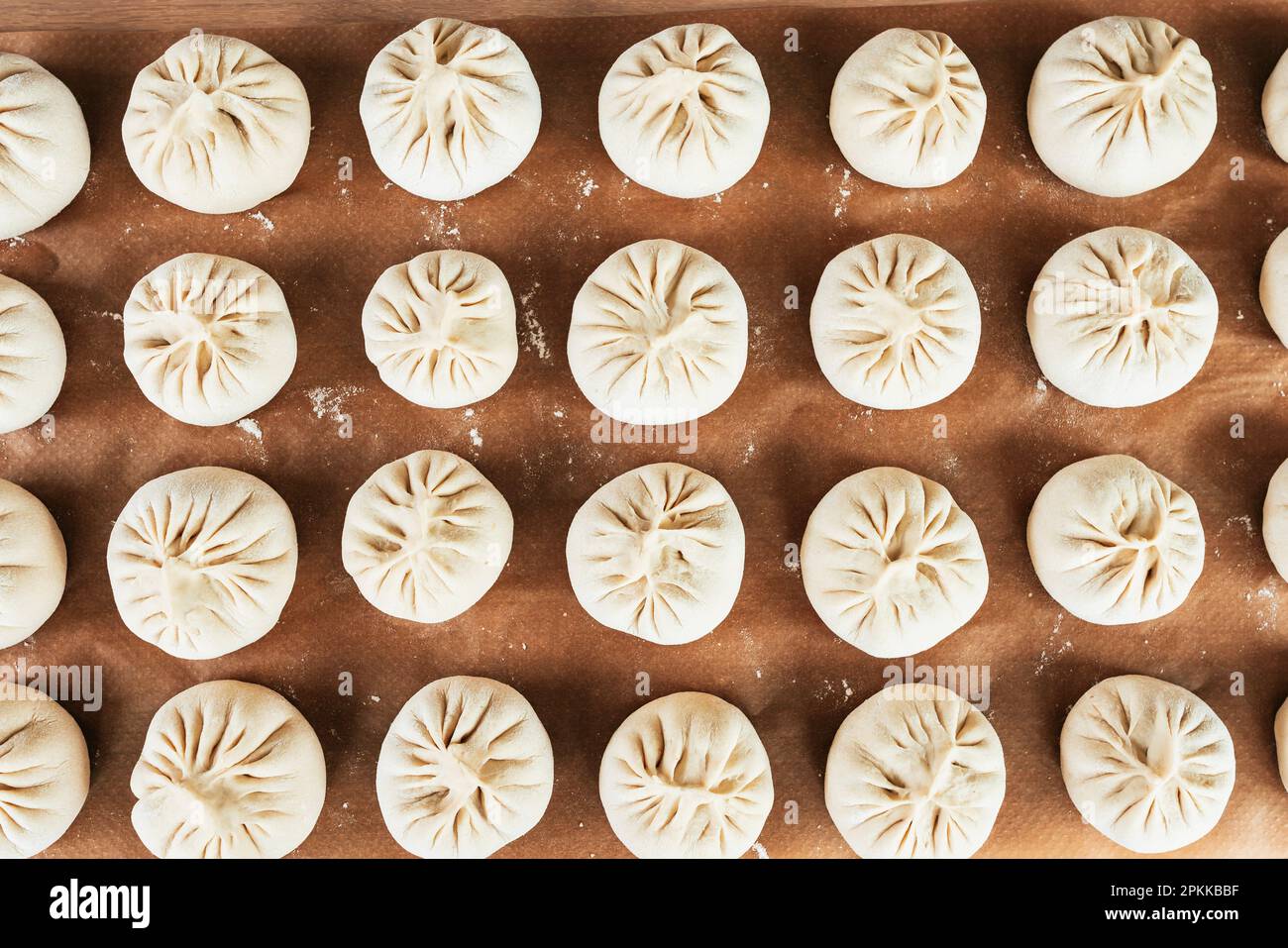 A group of bao is placed on a table waiting to be steamed. Bao, also ...