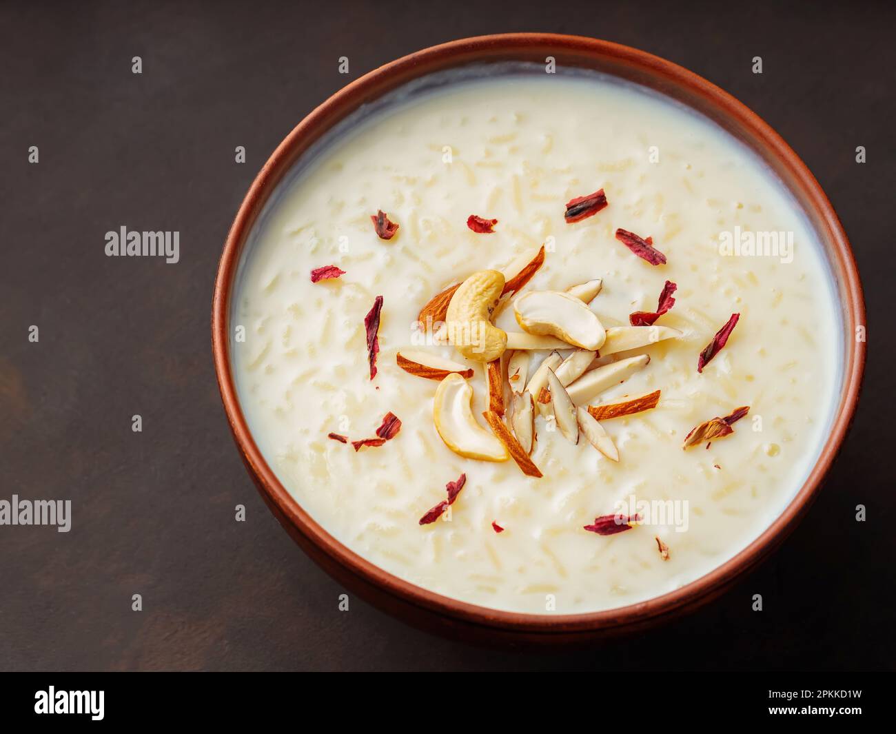 Creamy rice Kheer garnished with nuts and hibiscus. Bowl with rice ...