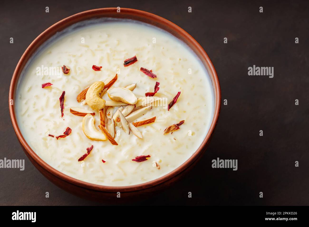 Creamy rice Kheer garnished with nuts and hibiscus. Bowl with rice ...