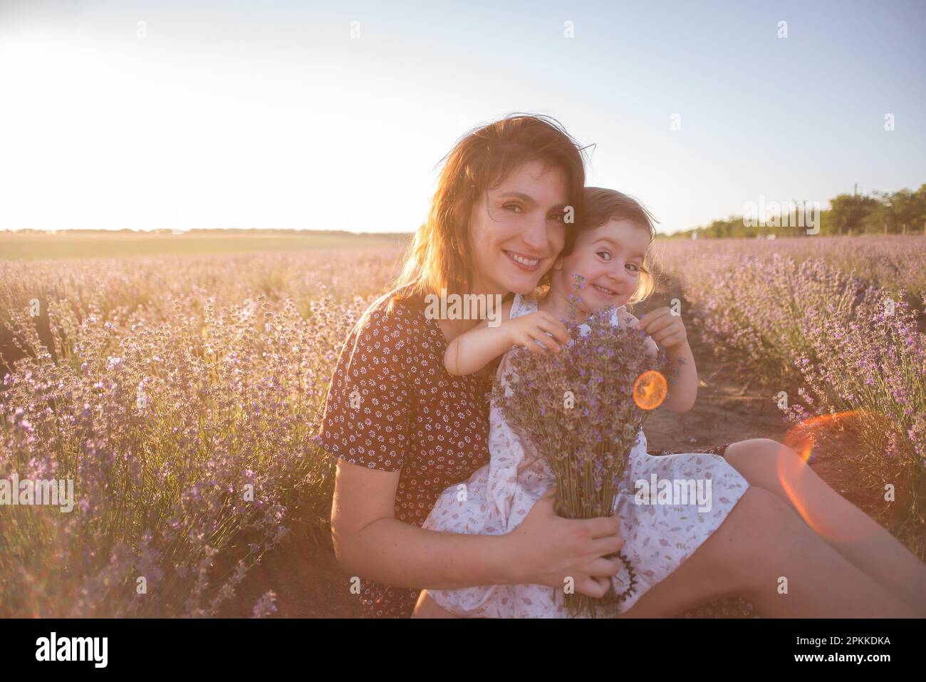 Portrait of brunette mother with little daughter sitting in purple ...