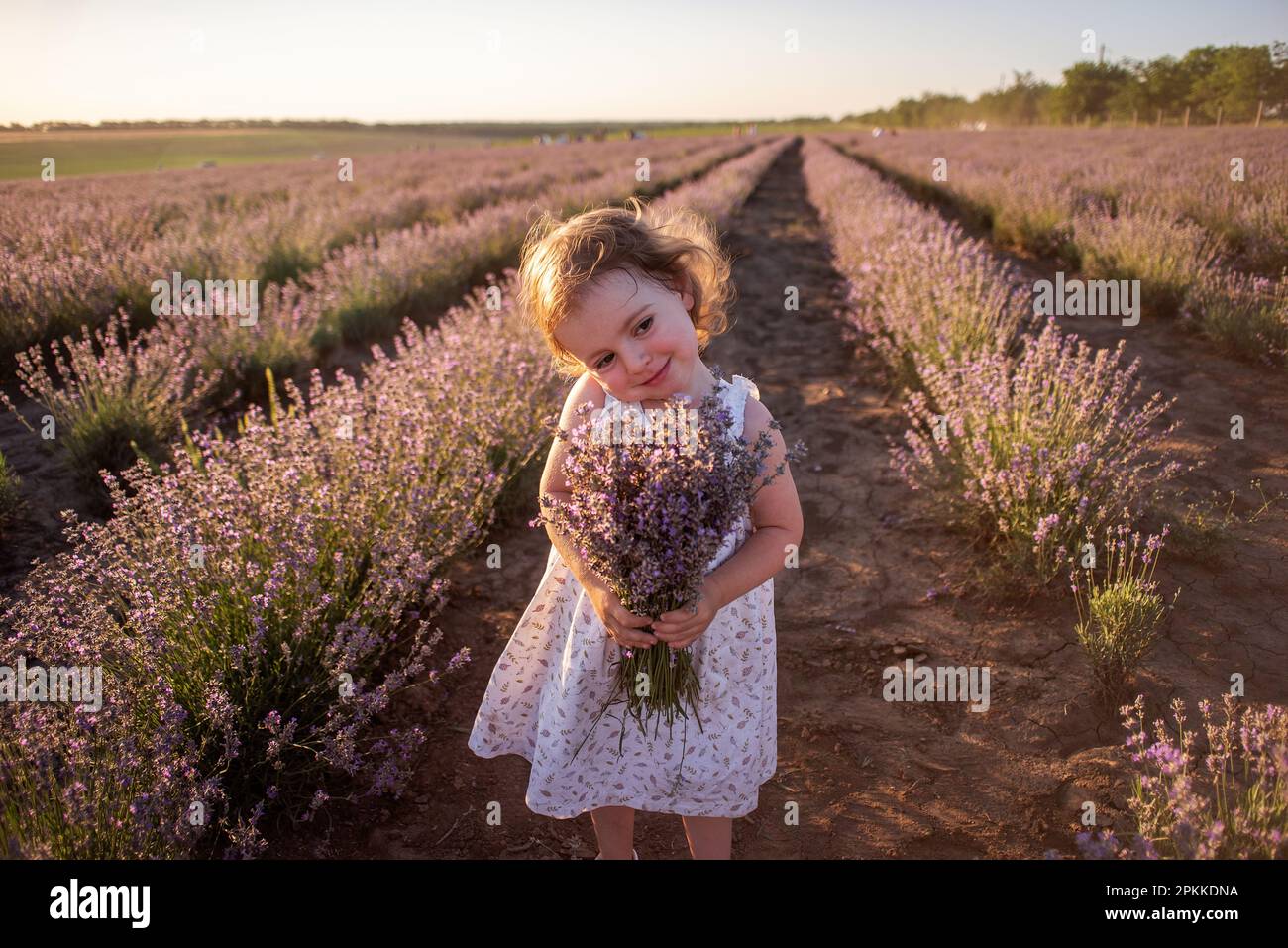 Close-up portrait of little girl in flower dress holding bouquet with ...