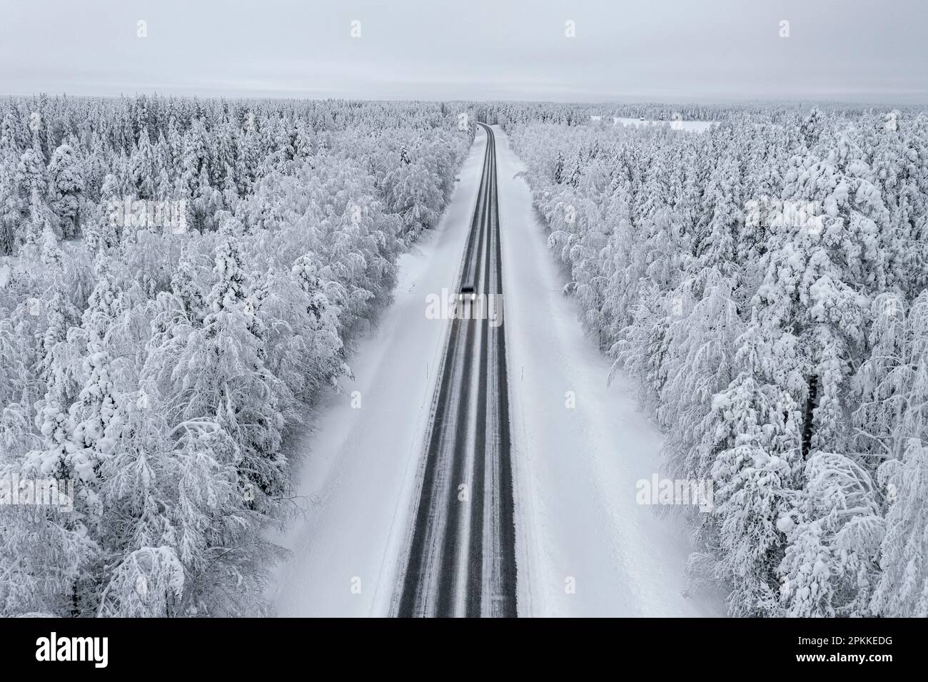 Overhead view of car driving on slippery empty road in the snowy forest ...