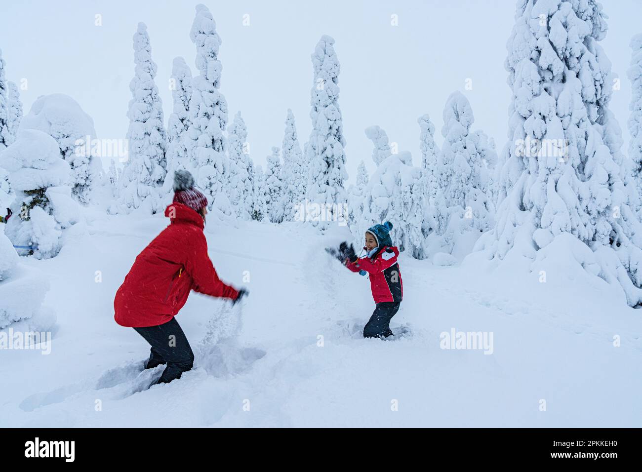 Cheerful mother and son enjoying playing with snow in the winter ...