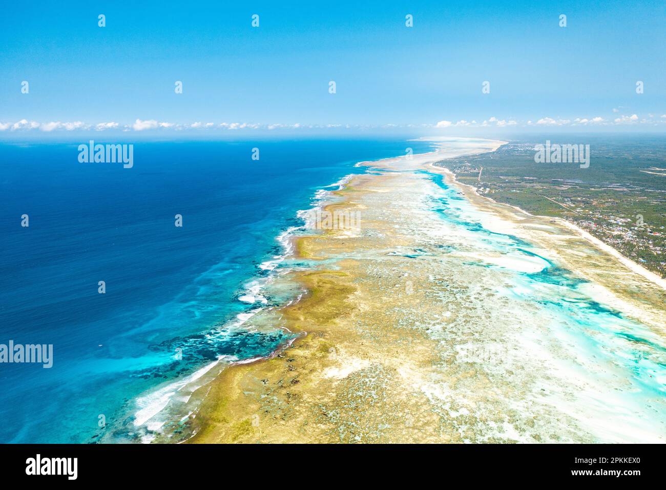 Waves crashing on sandbanks nearby an idyllic blue lagoon, aerial view ...