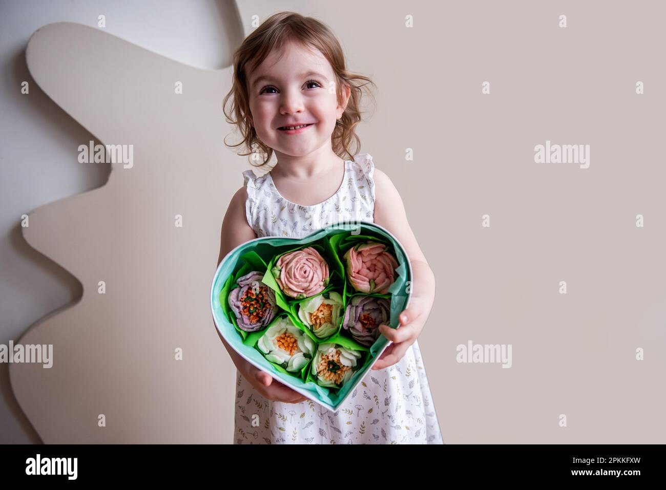 Little curly girl holds heart shaped box with homemade, sweet ...