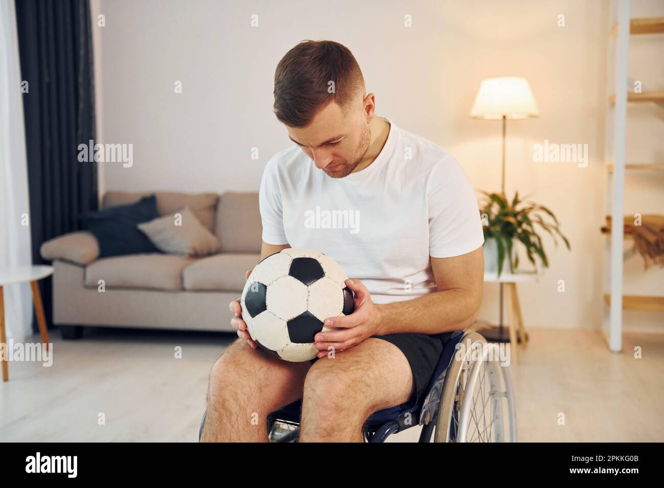 With soccer ball. Disabled man in wheelchair is at home Stock Photo - Alamy