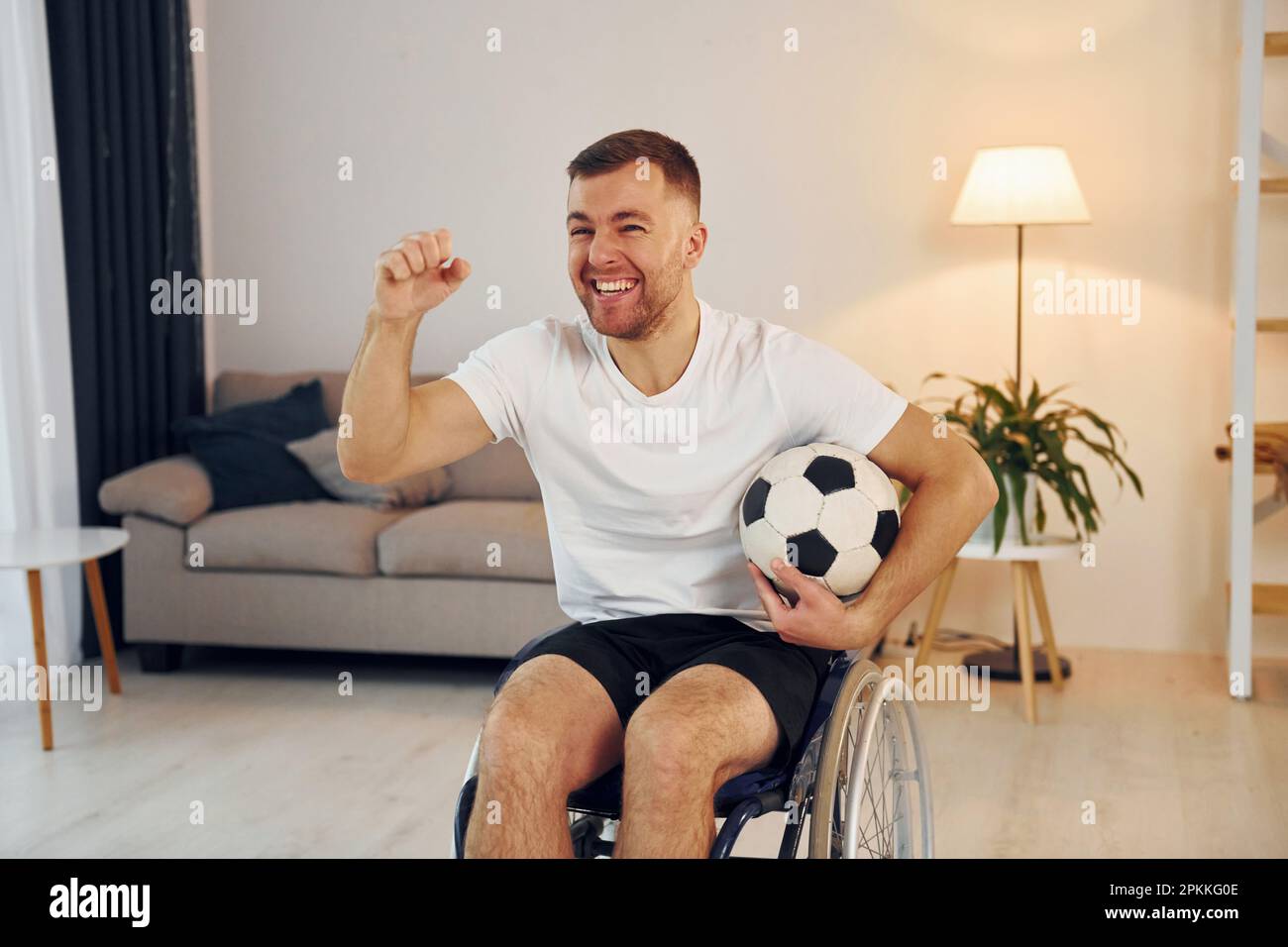 Soccer fan with ball. Disabled man in wheelchair is at home Stock Photo ...