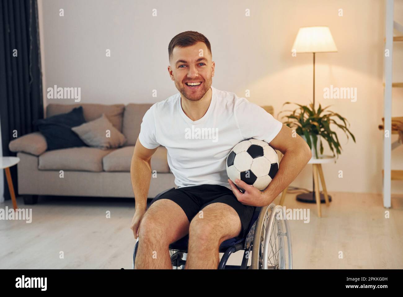 Soccer fan with ball. Disabled man in wheelchair is at home Stock Photo ...