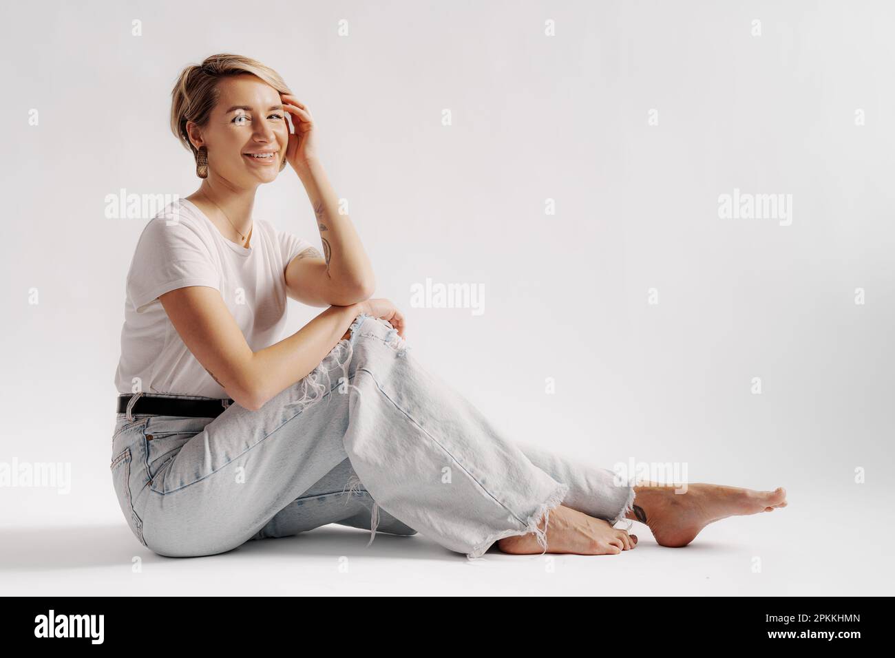 Barefoot young woman sitting on floor Stock Photo - Alamy