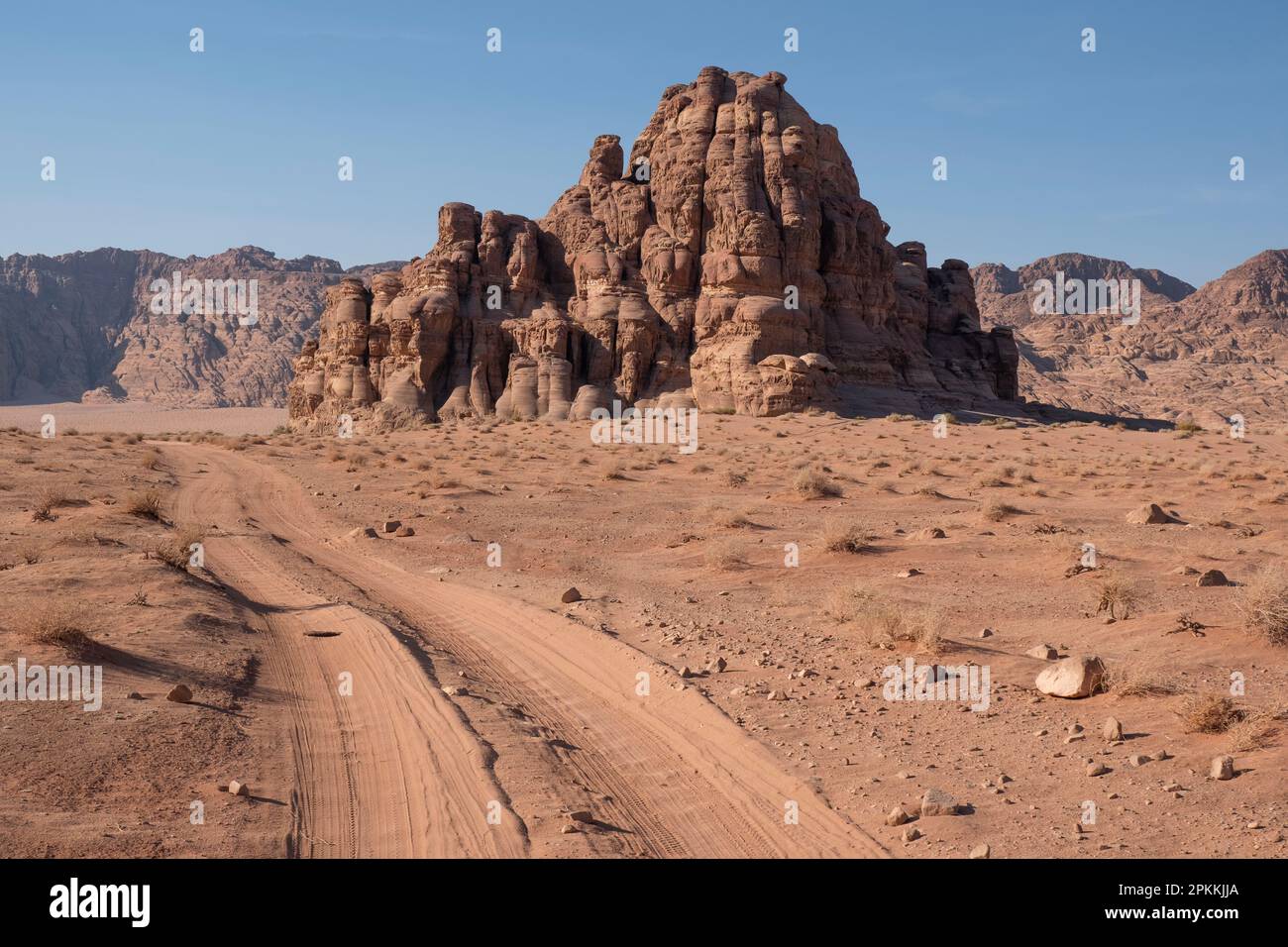 Off-road vehicle tracks in the sand of Wadi Rum leading to a rocky ...