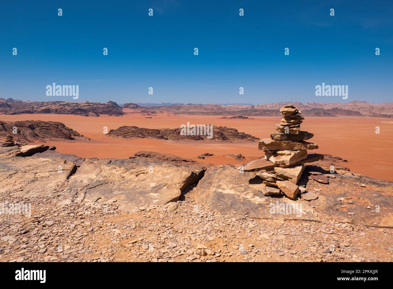 Wadi Rum red desert with some stone stacked in a pile in the foreground ...