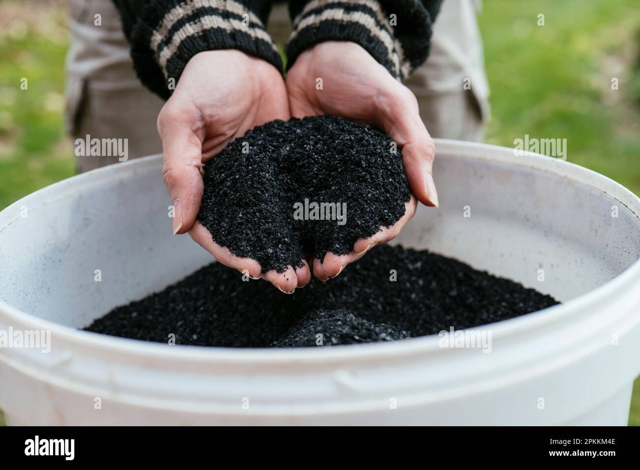 Man with a handful of biochar pellets made from herbs using pyrolysis ...