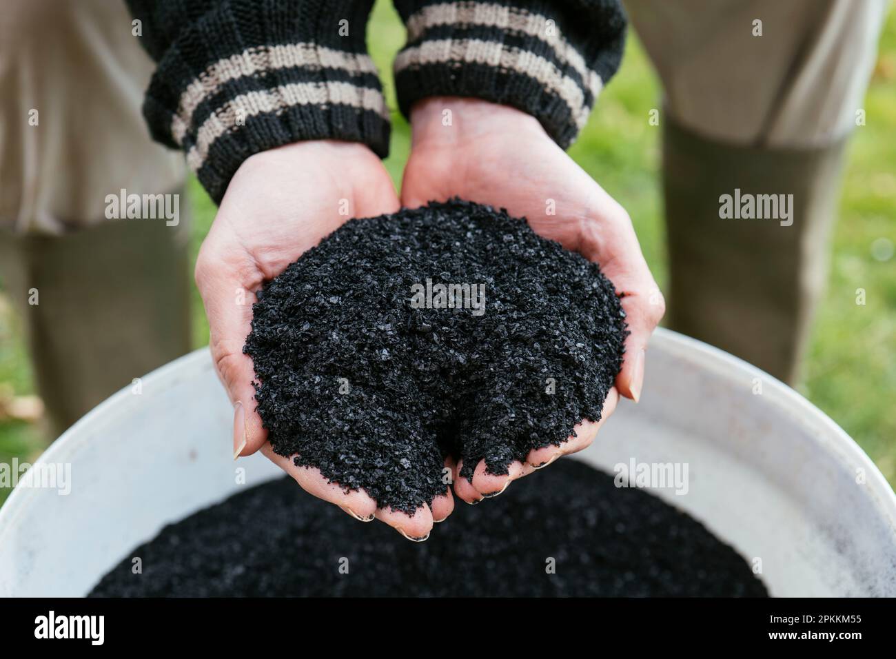 Man with a handful of biochar pellets made from herbs using pyrolysis ...