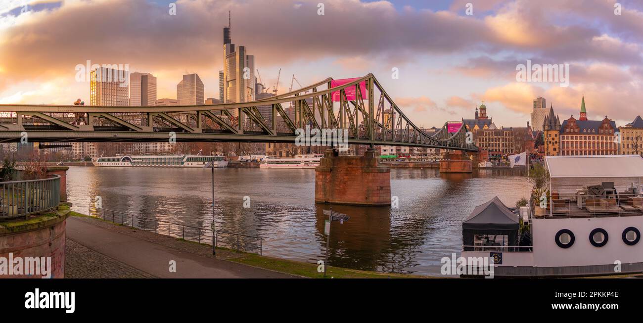View of city skyline, River Main and Iron Footbridge at sunset ...