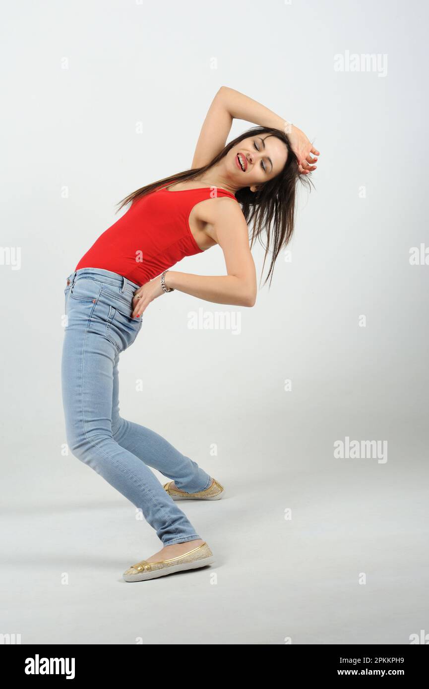 Beautiful young woman in red shirt and blue jeans posing in studio and ...