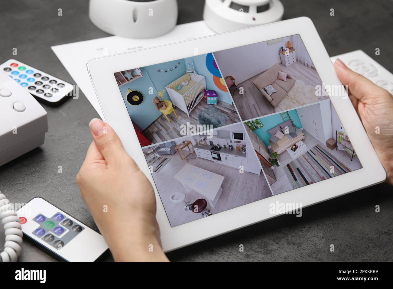 Woman monitoring CCTV cameras on tablet at grey table, closeup. Home ...