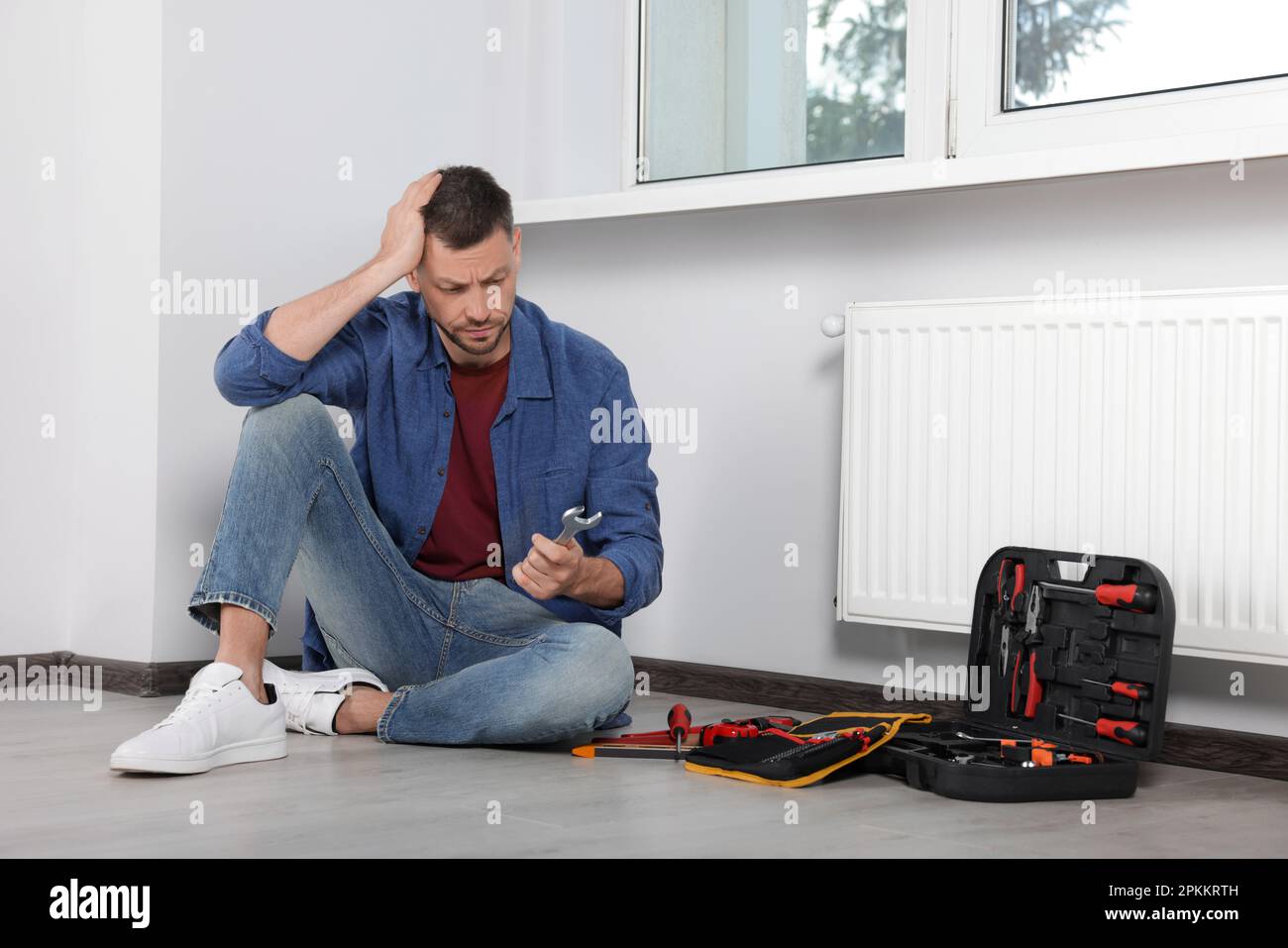Man holding wrench near box with tools indoors Stock Photo - Alamy
