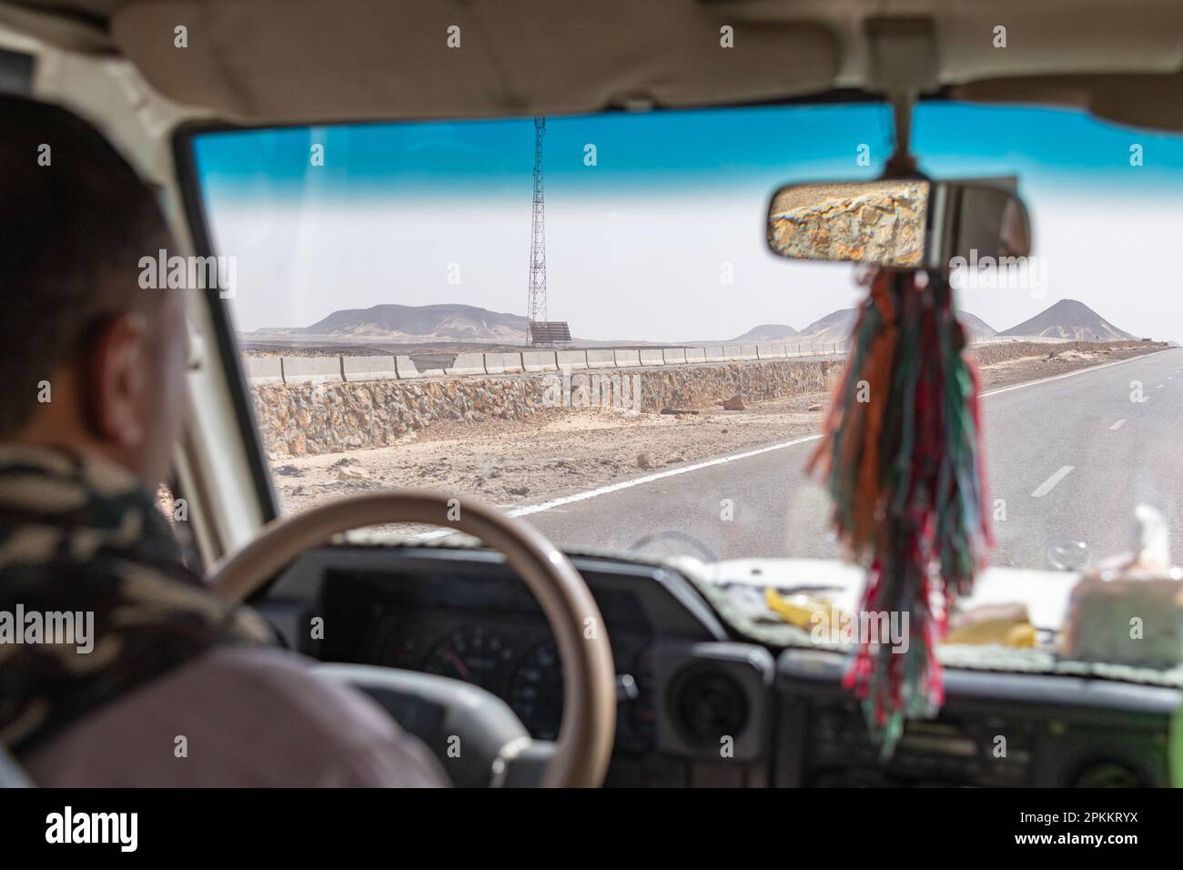 A tour guide driving a jeep down a highway in the desert in Egypt Stock ...