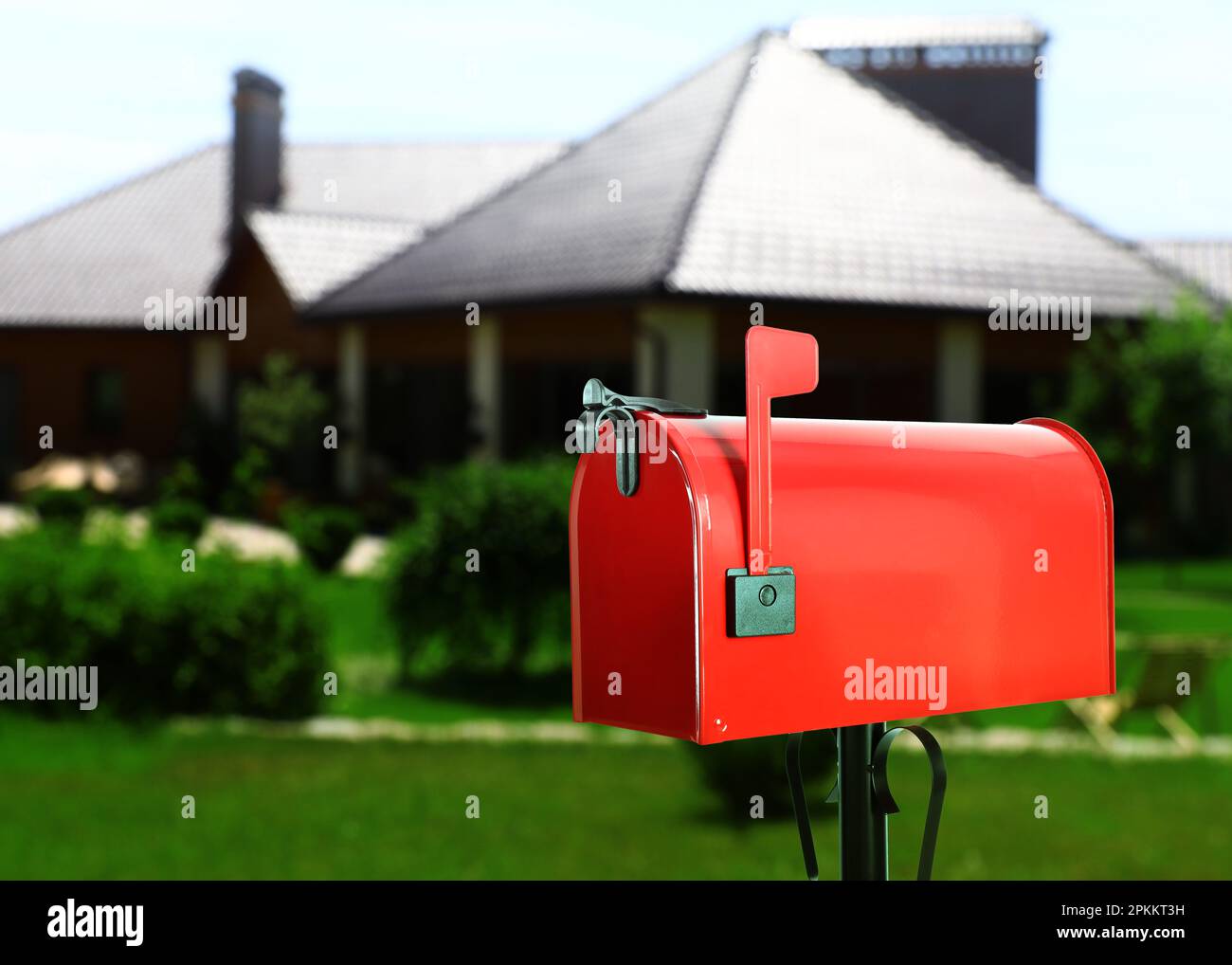 Red letter box and blurred view of modern house with beautiful garden ...