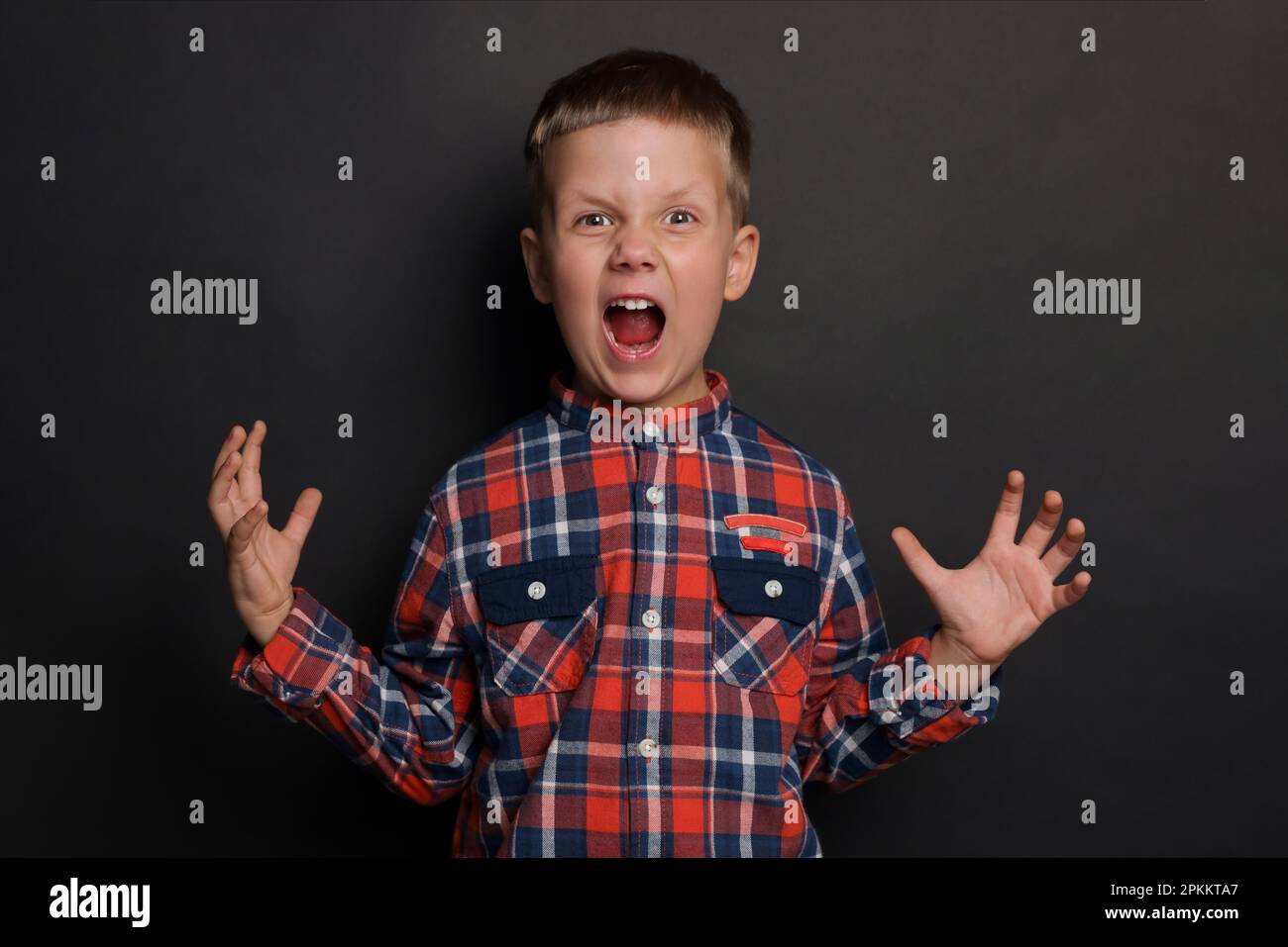 Angry little boy screaming on black background. Aggressive behavior ...