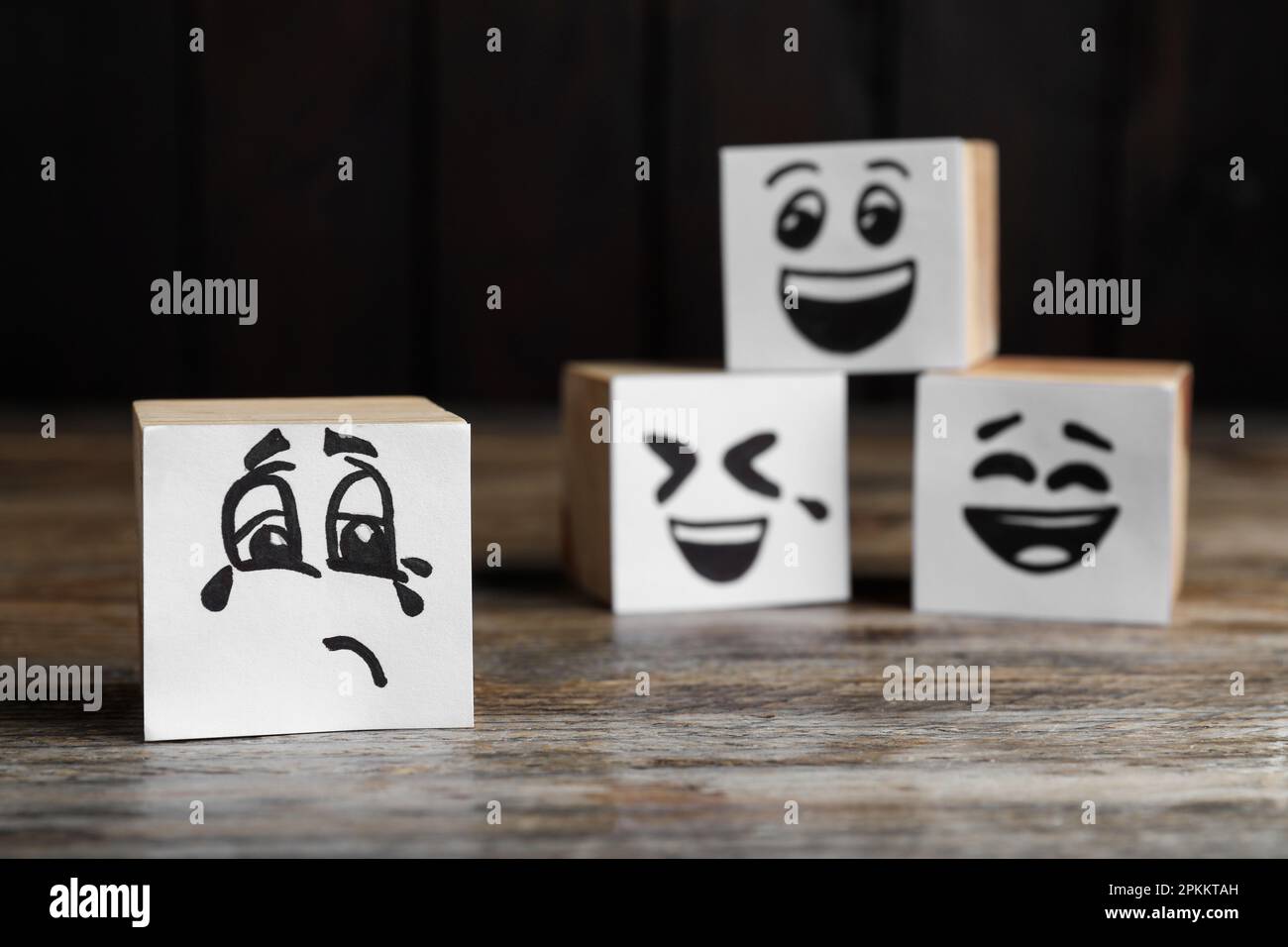 Cubes with sad and funny faces on wooden table. Bullying concept Stock ...