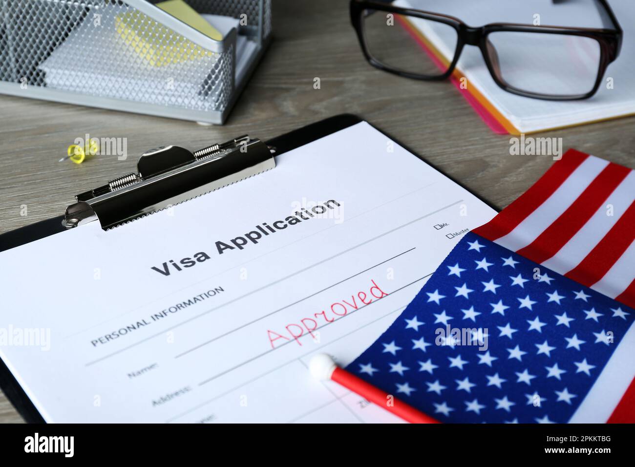 Visa application form with word Approved and American flag on wooden ...
